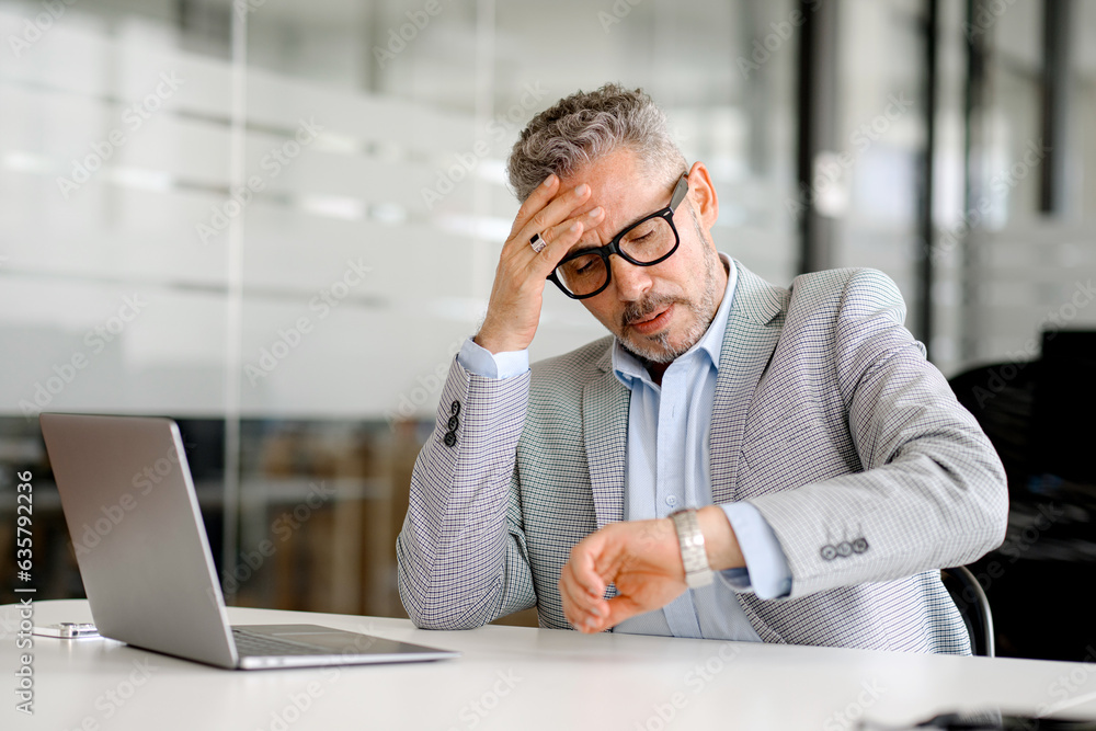 Disappointed mature businessman in formal wear looking at the watch on ...