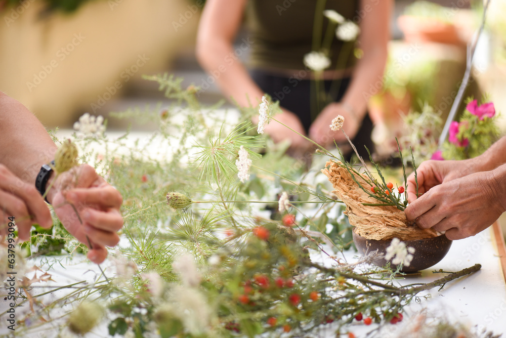 Detail of hands making flower arrangement, outdoor ikebana workshop ...