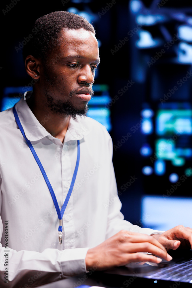 African american IT developer in data center using laptop to set up ...