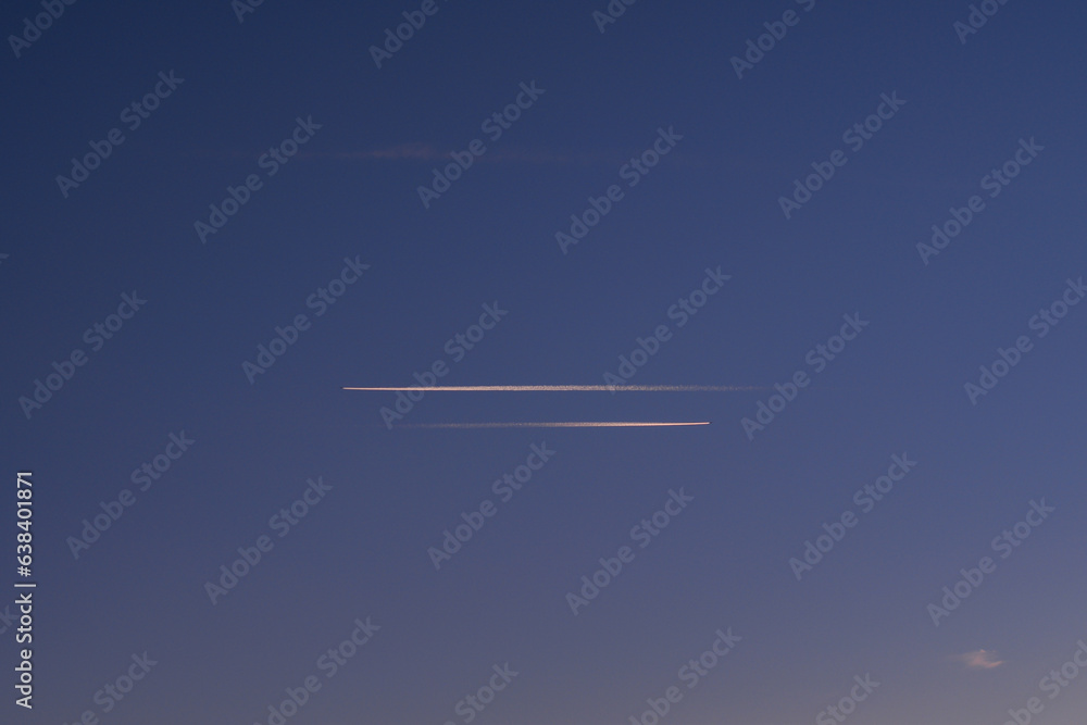 Two passenger planes passing parallel in the blue sky. Traces made by ...