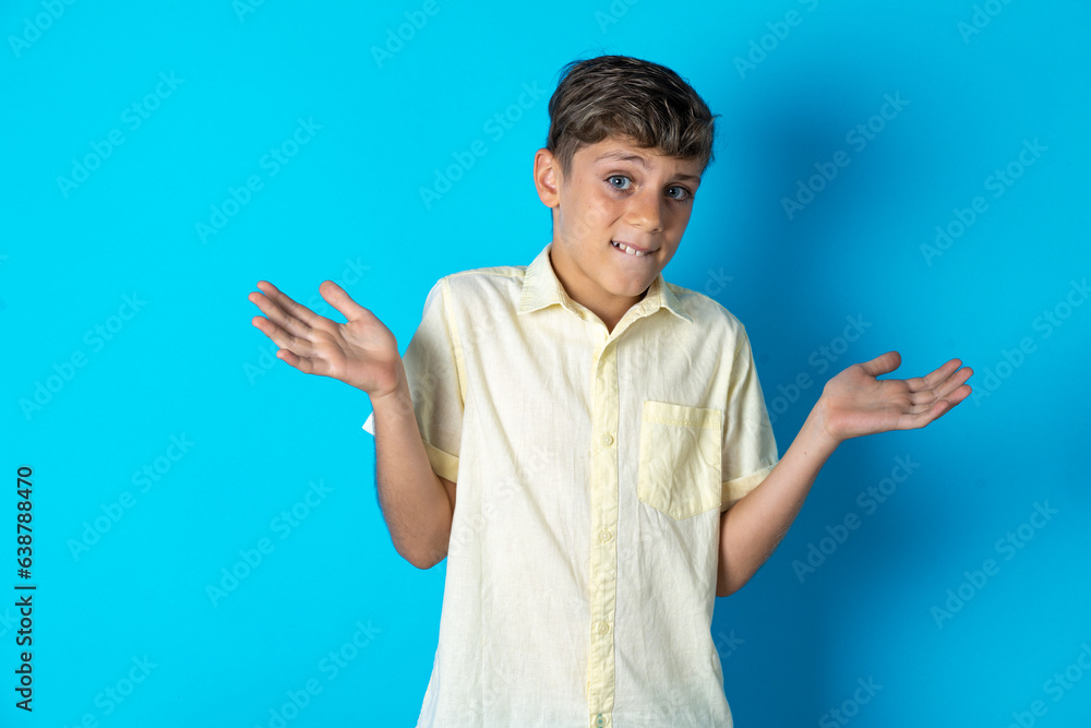 Clueless Beautiful kid boy wearing casual shirt shrugs shoulders with ...