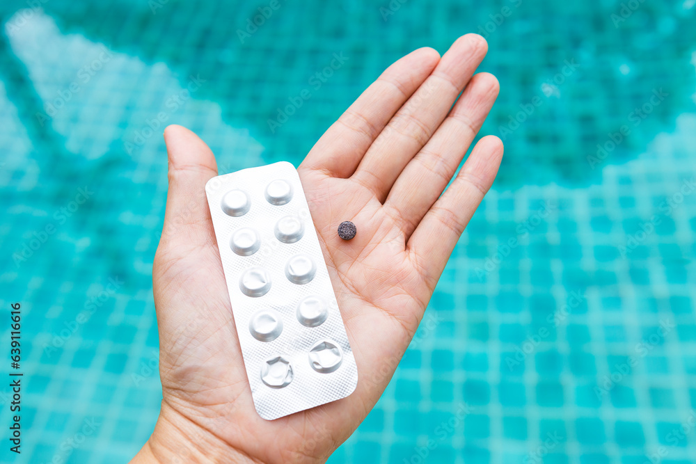 Expired regents tablet in girl hand over blurred swimming pool ...