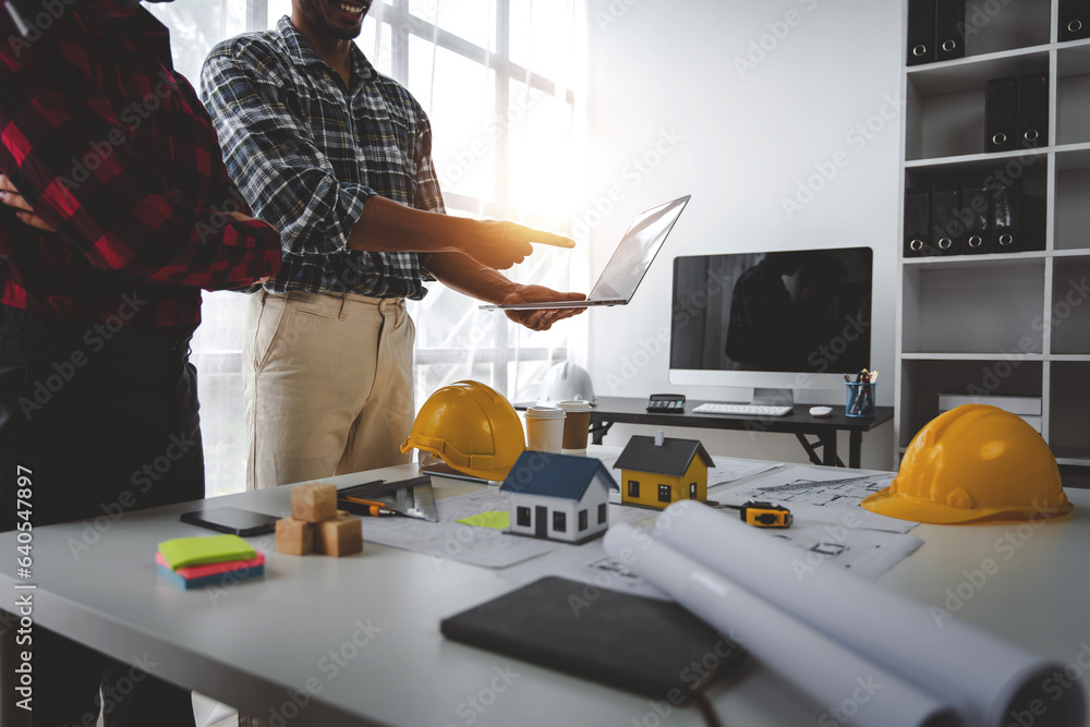 Engineers work as a team with blueprints for architectural plans ...