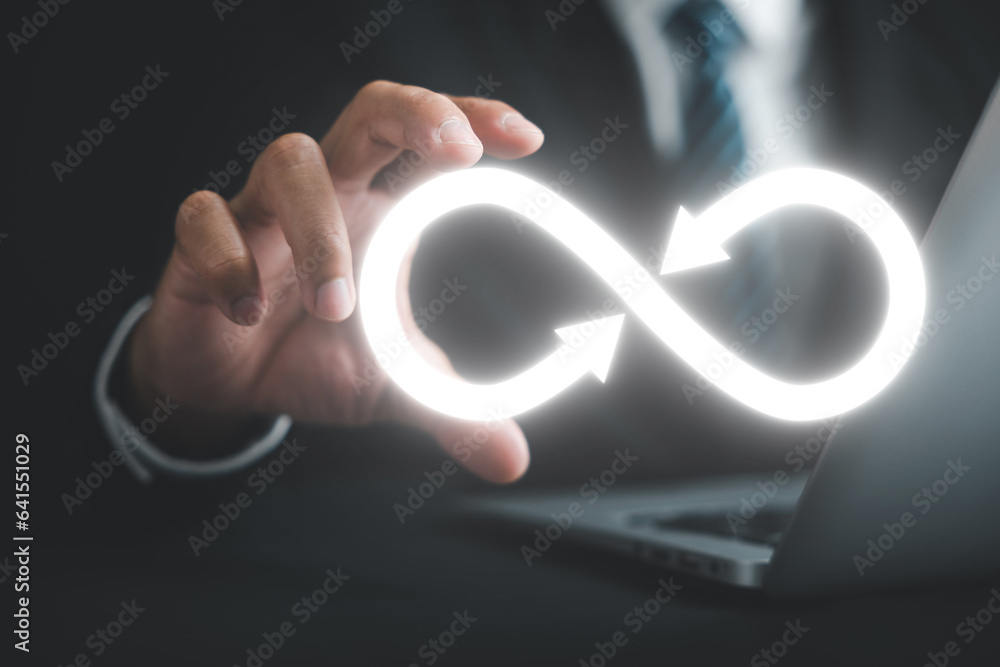 Circular infinity symbol held by businessman on dark background ...