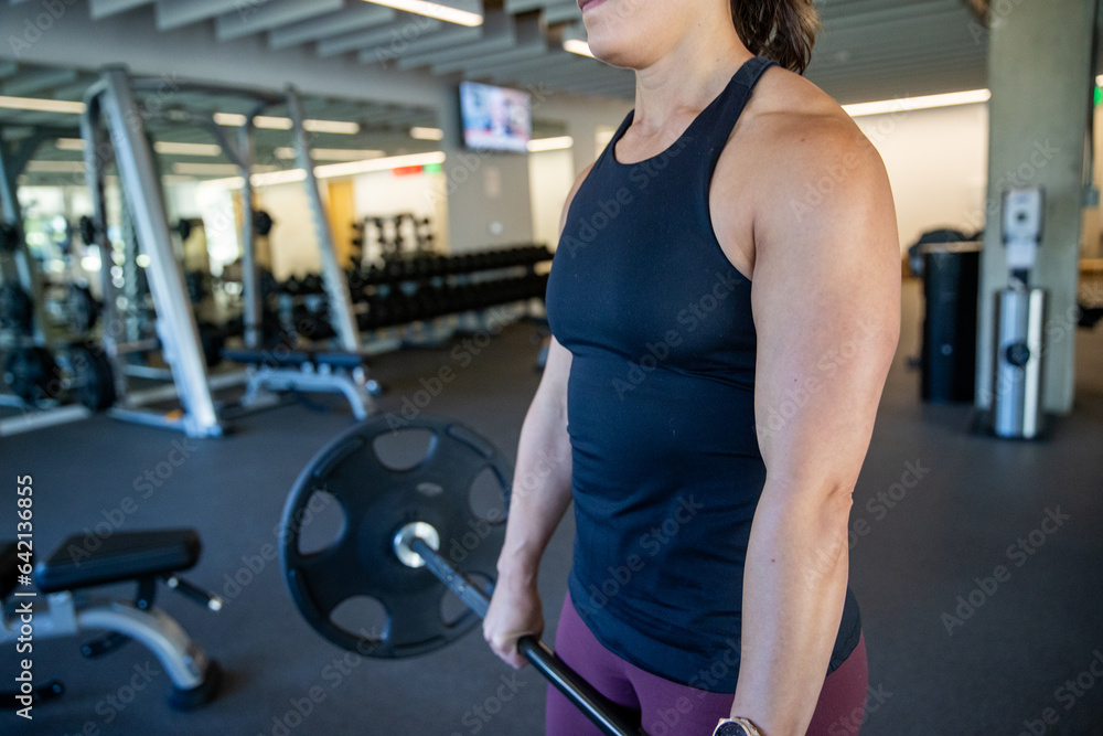 Strong, muscular woman lifting weights in gym during workout ...