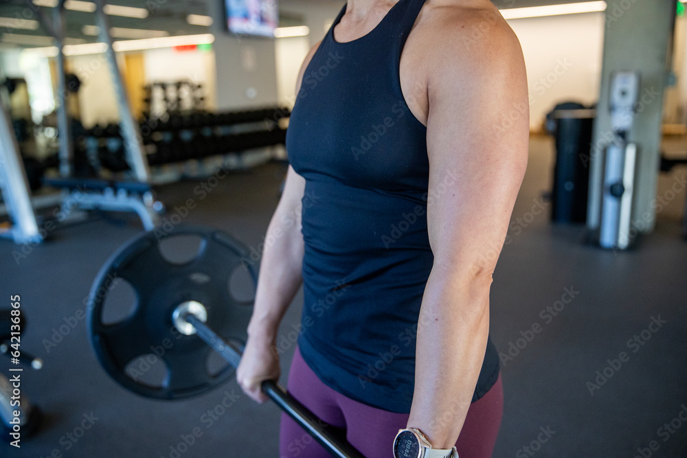 Strong, muscular woman lifting weights in gym during workout ...