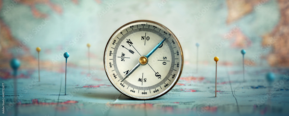 Magnetic compass and location marking with a pin on routes on world map ...