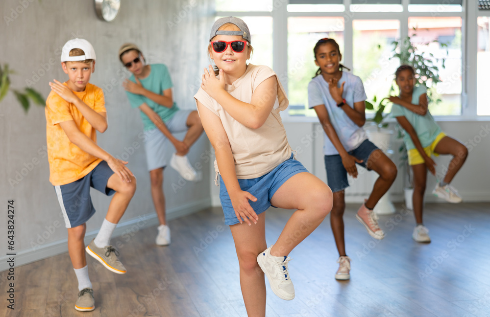 Smiling cute tween girl performing krump movements with group in dance ...