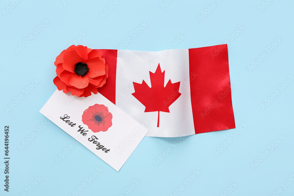 Poppy flowers, flag of Canada and card with text LEST WE FORGET on blue ...