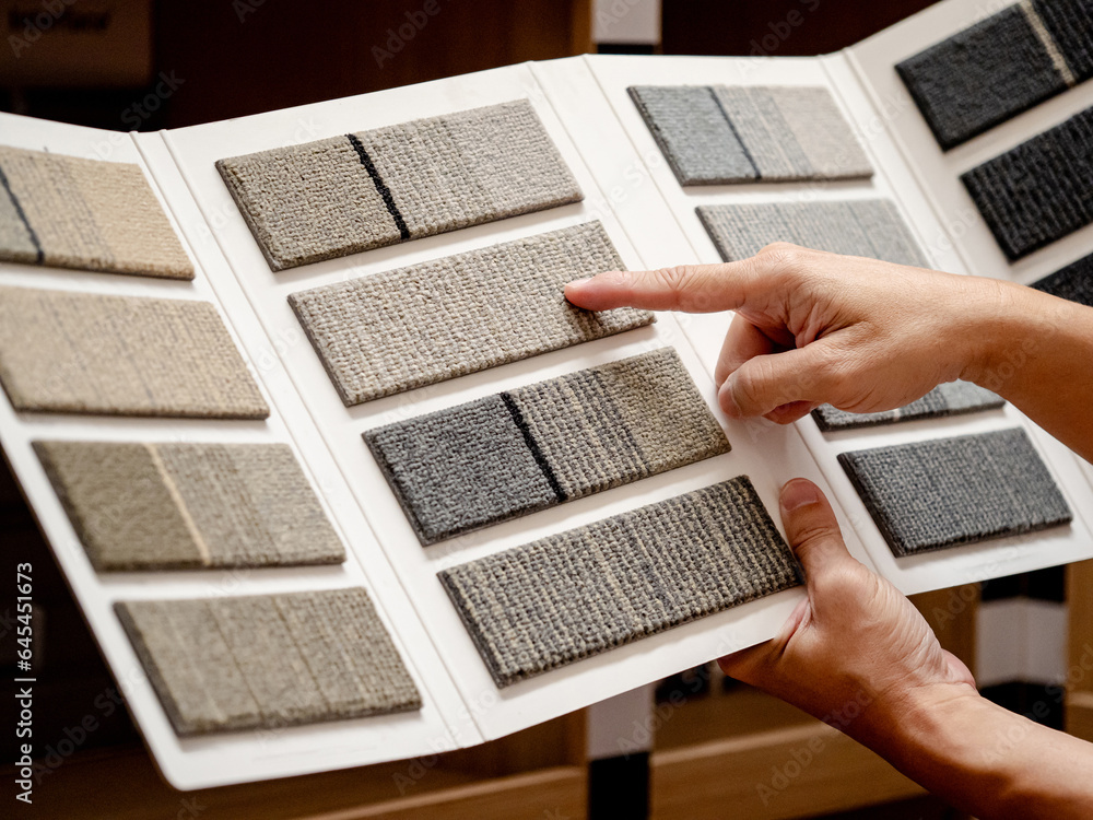 Designer hand pointing on fabric tile carpet samples catalog in ...