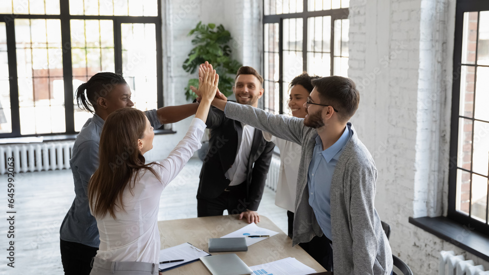 Excited multiracial colleagues give high five celebrate shared company ...