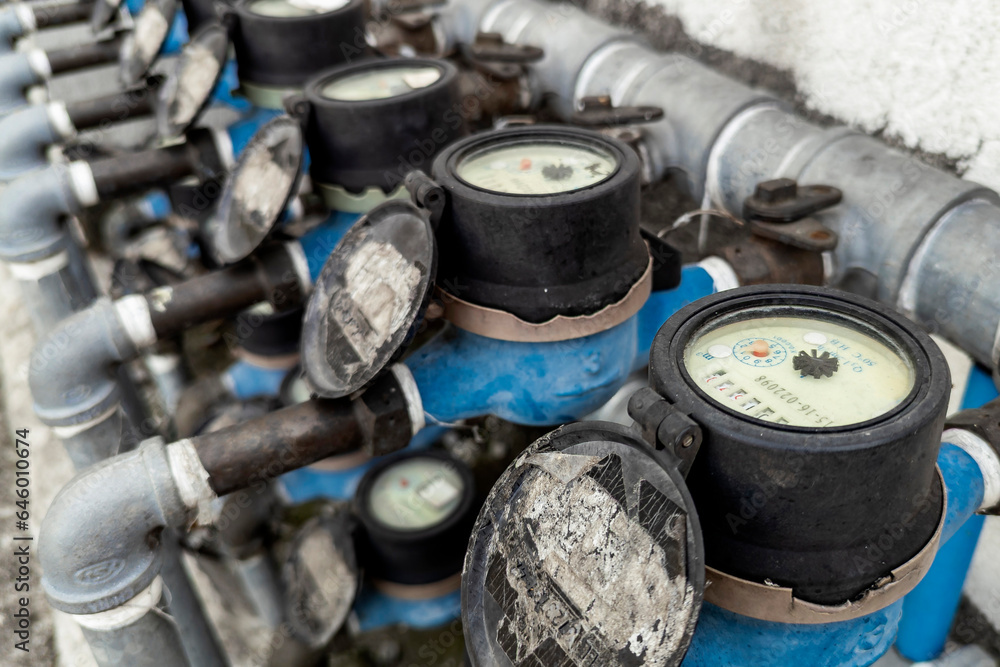 Several analog water meters installed outside an apartment building or ...