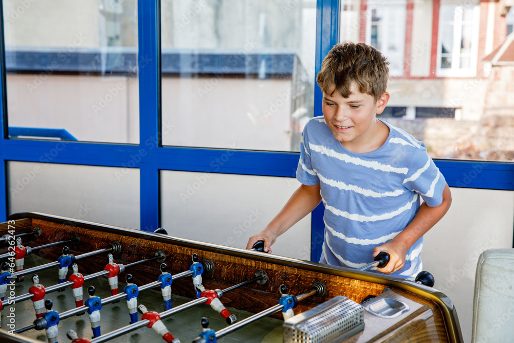 Smiling school boy playing table soccer. Happy excited child having fun ...