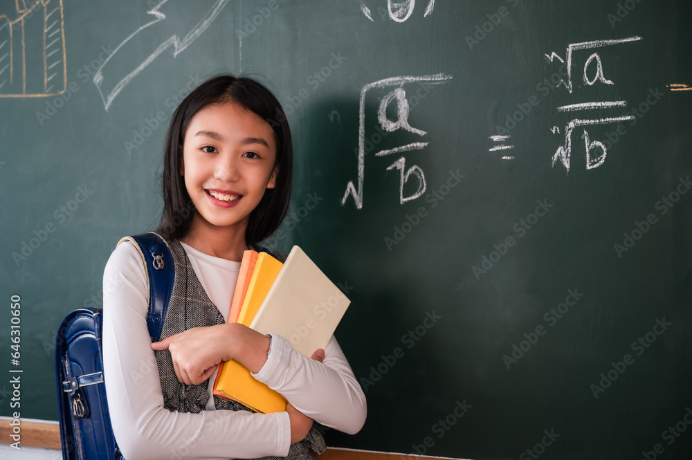 Happy cute child girl student carrying a backpack and holding books ...
