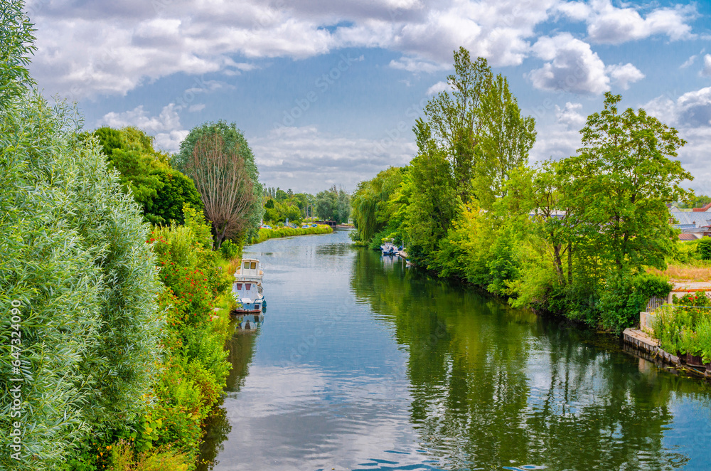 Water canal with green trees on bank of River Somme and small motor ...