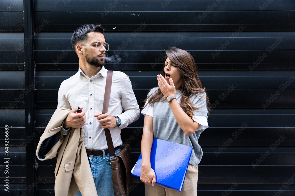 Young business woman is standing next to a colleague who is smoking a ...