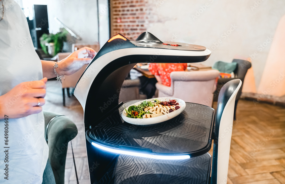 Robot waiter serve food at modern restaurant table.Offering innovation ...