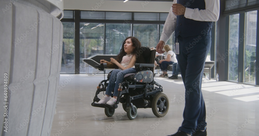 Woman with SMA disability rides in clinic entrance on motorized ...