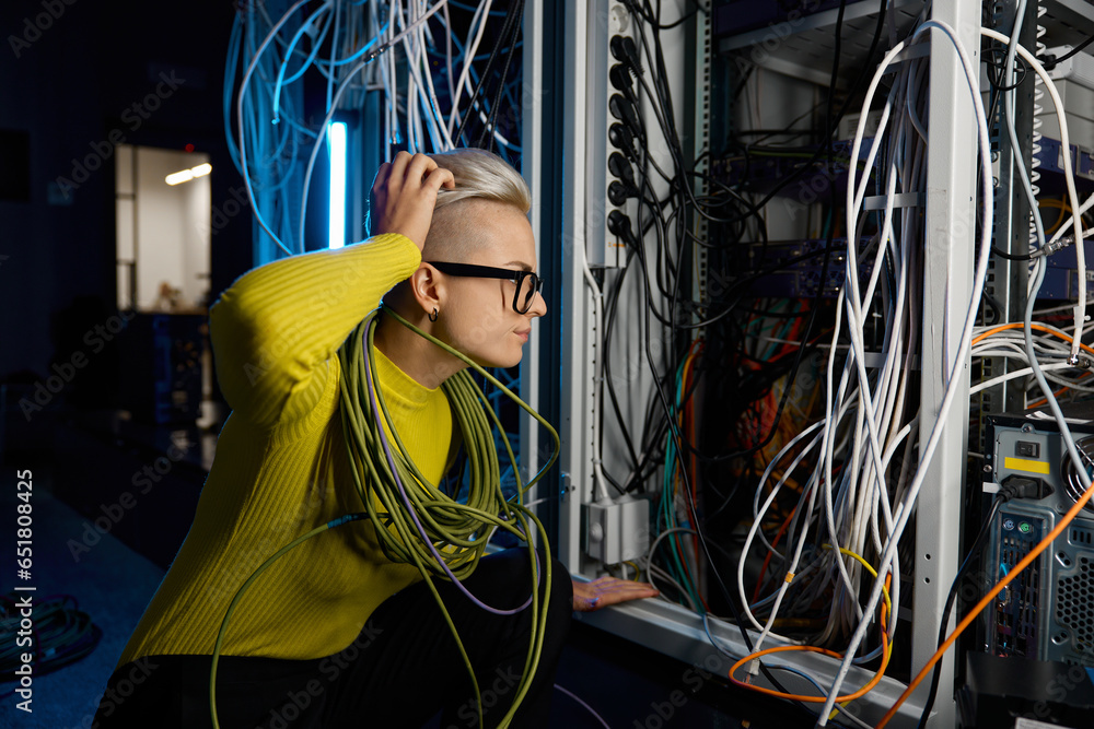 Confused female data center technician inspecting computer system and ...