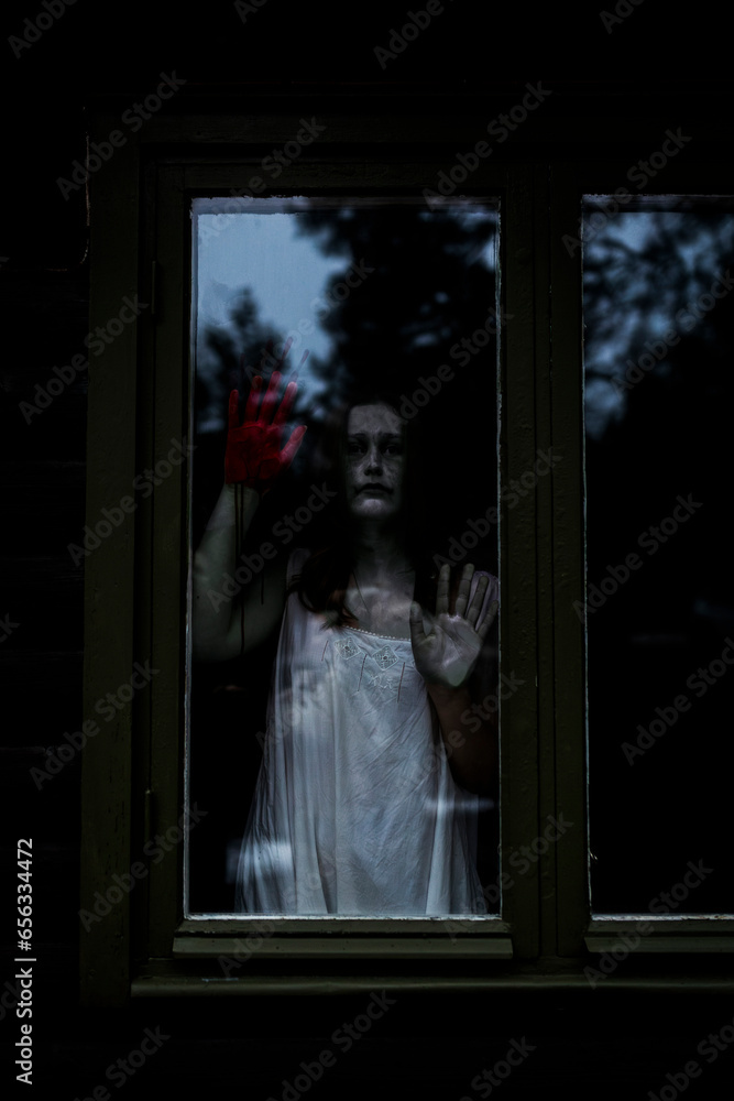 Female ghost with blood on hand seen through glass window of haunted ...