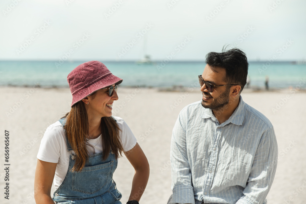 Smiling couple having conversation on beach in front of sea Stock Photo ...