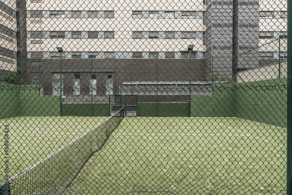 Paddle tennis court closed with metal fences, light bulbs and painted ...