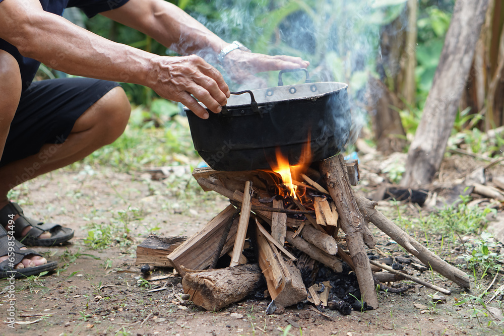 Close up man holds old black pot to cook on bonfire. Concept, cooking ...