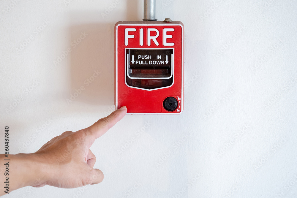 Emergency fire warning system pull station. Hand pointing at red fire ...