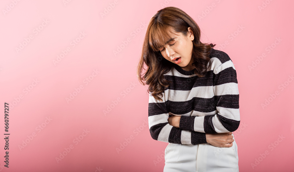 Portrait of a young Asian woman with stomachache, experiencing ...