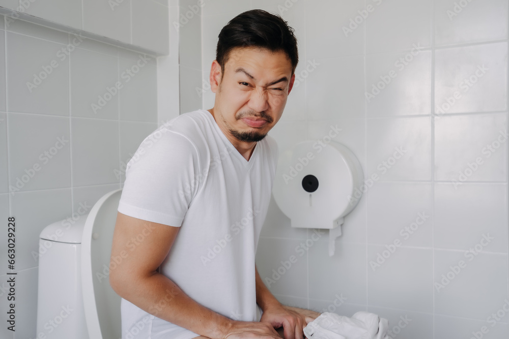 Stock-Foto „Funny face asian man pushing poop in the toilet as he has ...