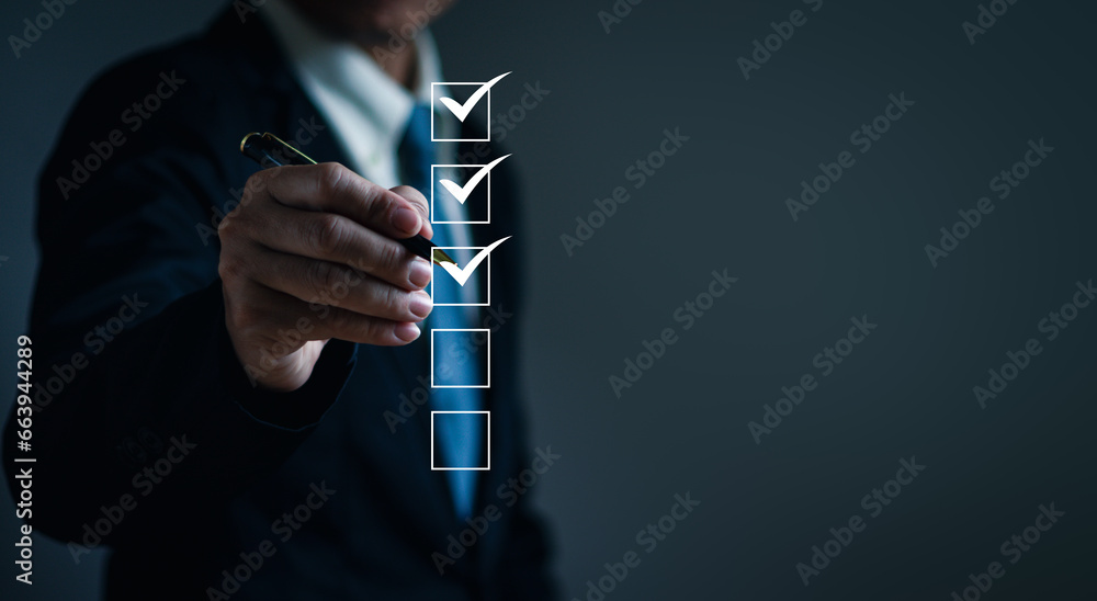 Businessman uses a pen to tick off checkboxes on a business performance ...