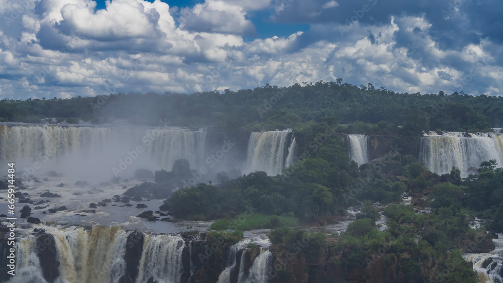 Cascades of waterfalls collapse from ledges of rocks. Spray, fog. Green ...