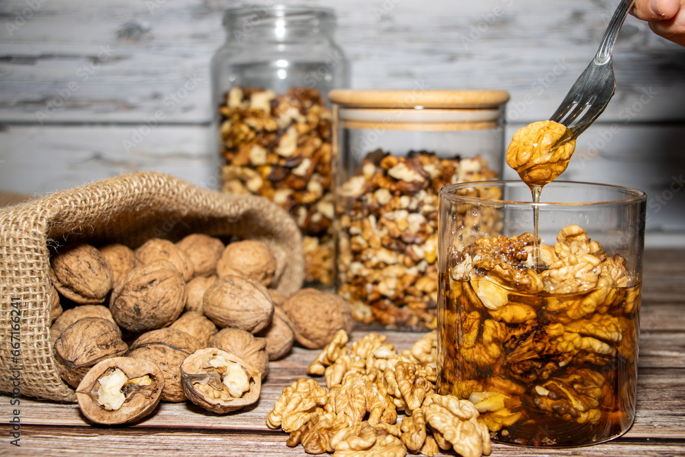 Jar full of nuts with honey removing one with a fork surrounded by ...