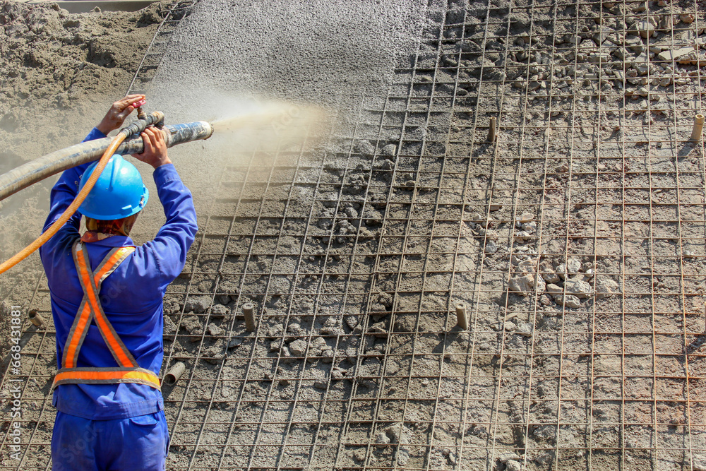 A worker is doing the shotcrete process, where the process is by firing ...