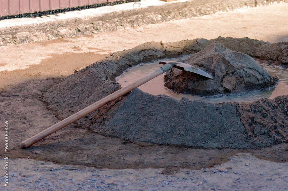 A mixture of cement and sand is soaked in water to mix the concrete by ...