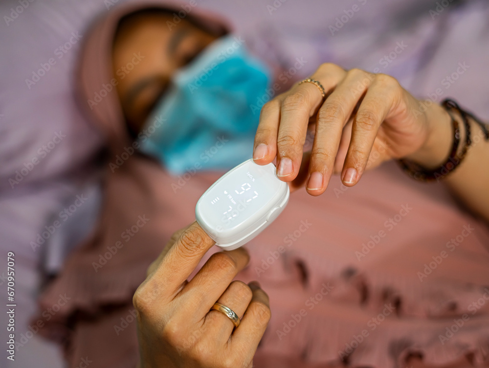 Pulse oximeter on a woman finger. A patient in a medical mask measures ...