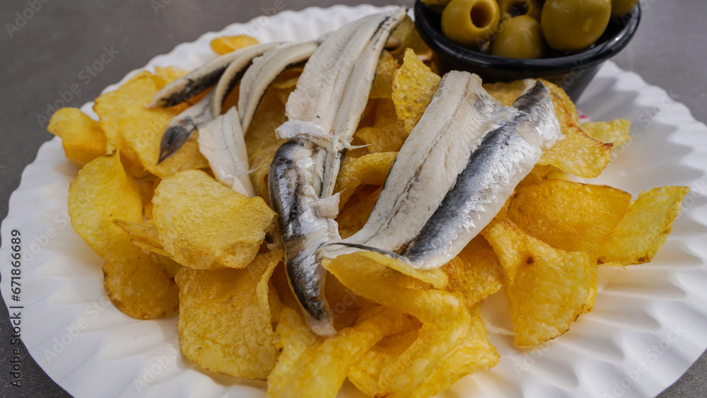 aperitivo de plato de cartón con patatas fritas, boquerones a la ...
