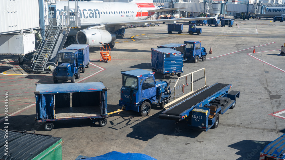Baggage carts near an American Airlines aircraft. Stock Photo | Adobe Stock
