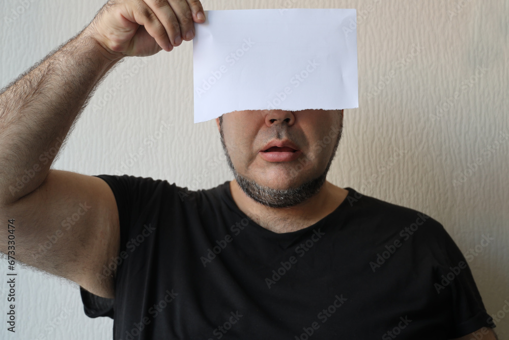 Portrait of a man holding a piece of white paper behind eyes. isolated ...