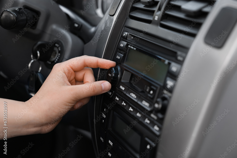 Listening to radio while driving. Woman turning volume button on ...