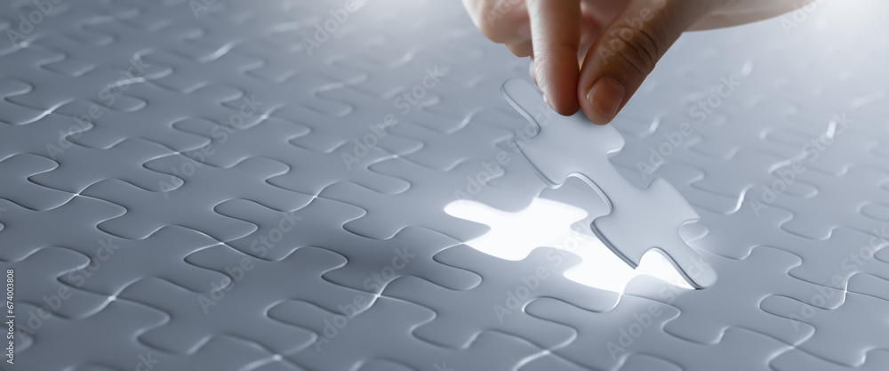 Hand put the last piece of white jigsaw puzzle to complete the mission ...