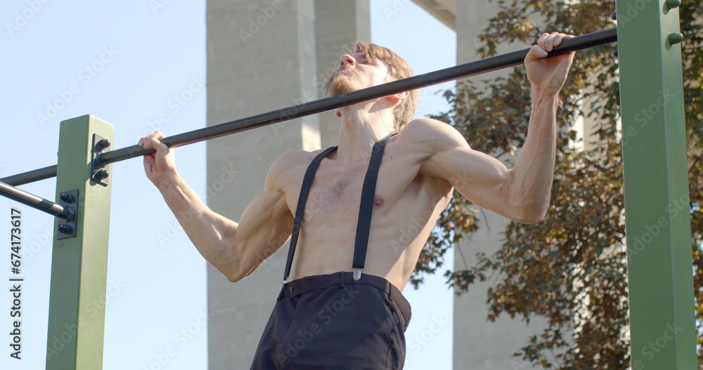 Man demonstrates masculinity while exercising outdoors. Pull-ups with ...