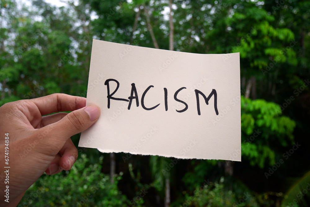 Hand holding white Paper with racism text in solative on nature ...
