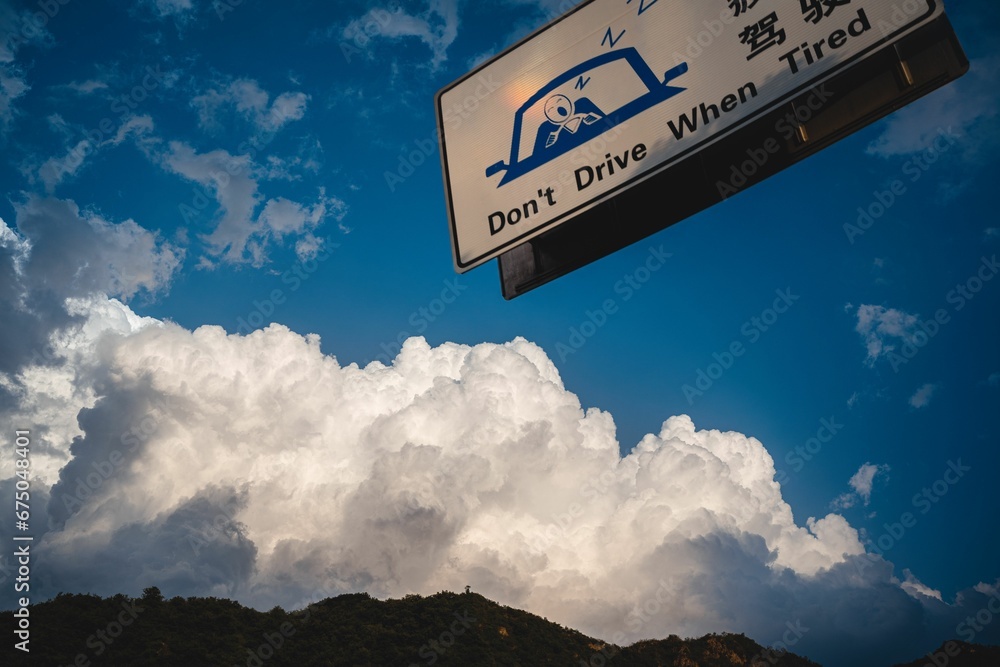 Warning sign reminding drivers to not drive when tired against a blue ...