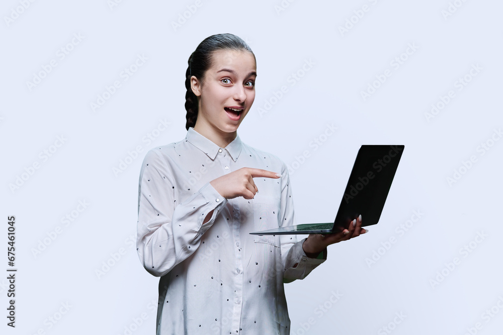 Teenage girl student using laptop, on white background, pointing at ...
