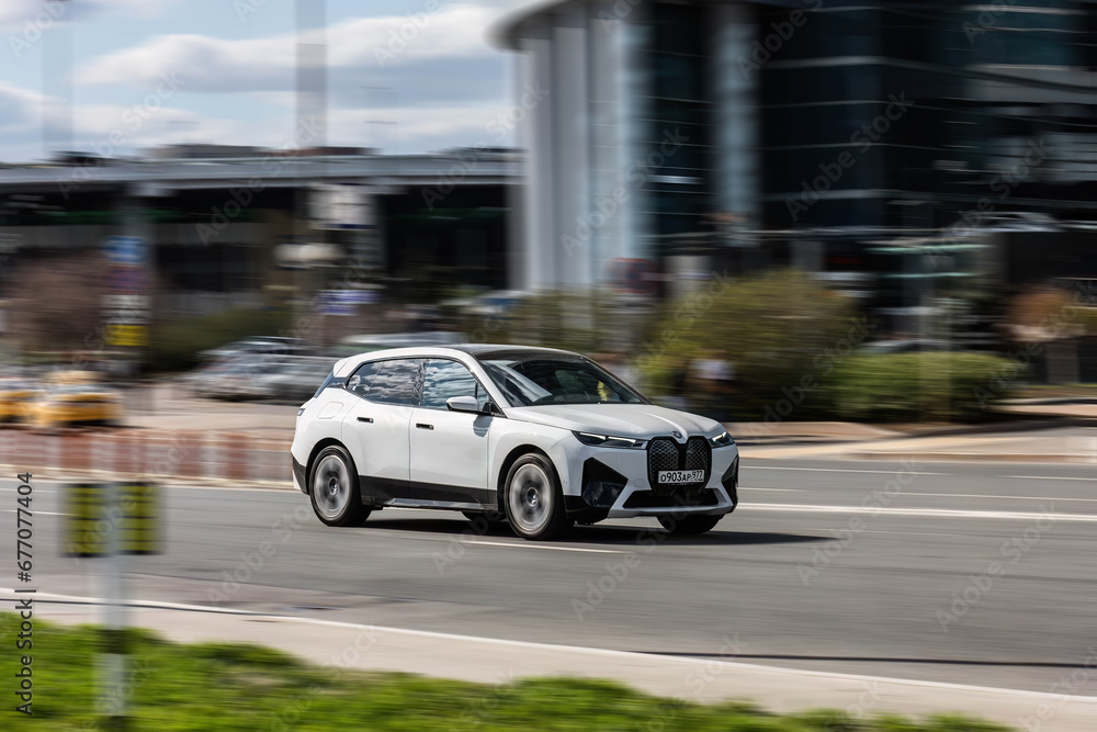 BMW iX EV car moving on the street. Modern crossover SUV driving along ...