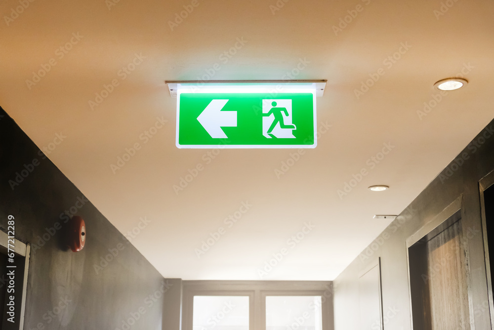Lighted glowing green emergency exit signs in an office hallway with ...