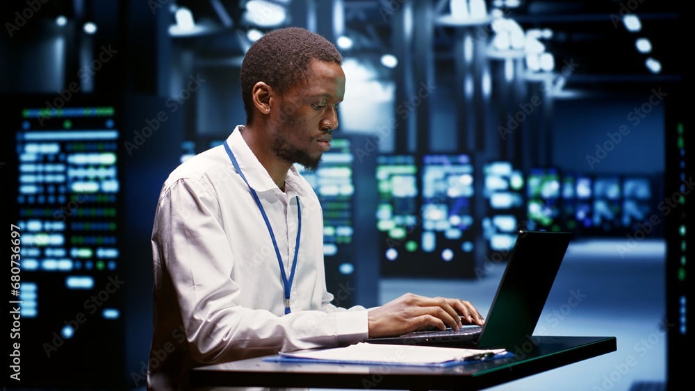 Computer scientist using laptop to debug servers cabinets helping companies manage databases ...