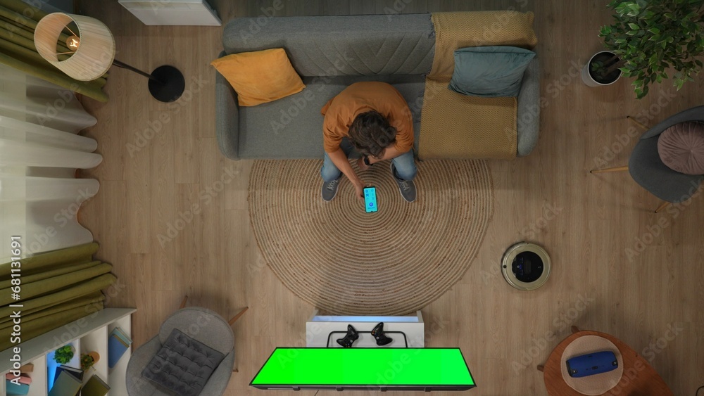 Top view of man sitting on the sofa holding smartphone looking at app ...