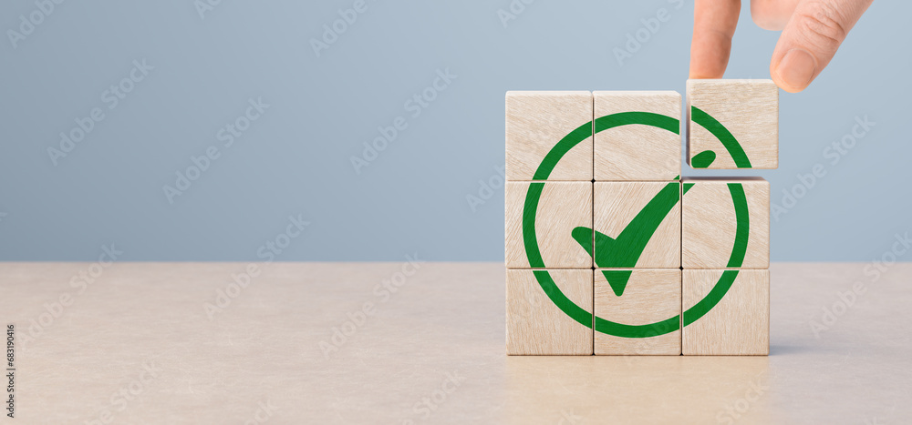 Wooden blocks and green check mark icon with hand on table background ...